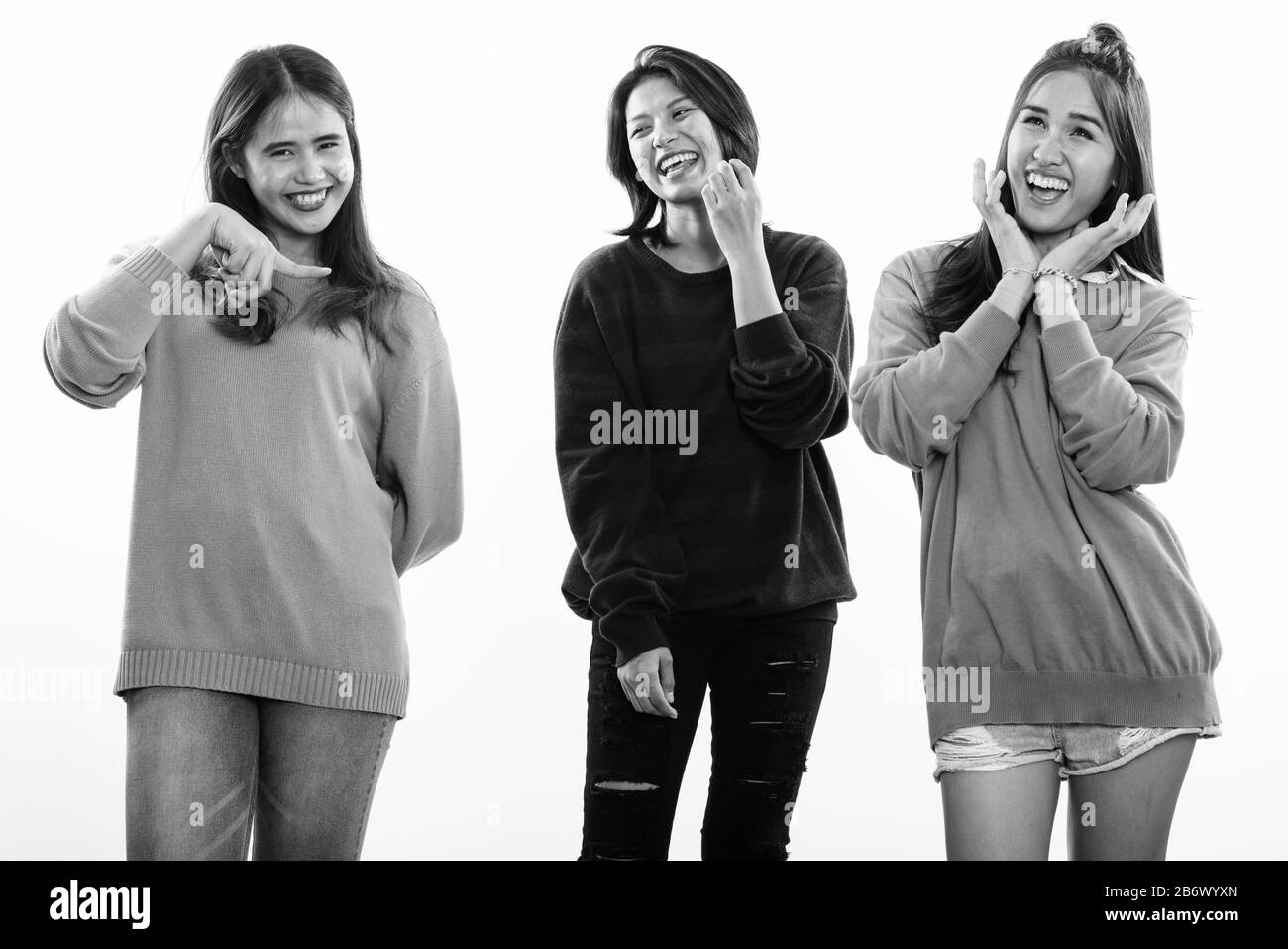 Three happy young Asian woman friends smiling and making funny faces ...
