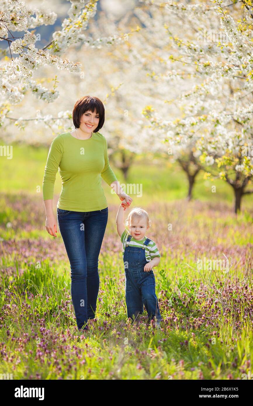 Happy woman and child in the blooming spring garden. Mum and son ...