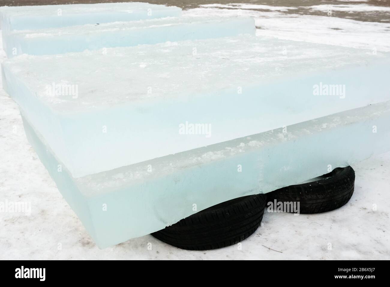 Ice blocks lie on rubber tires. Black tires as a stand. Ice for ...