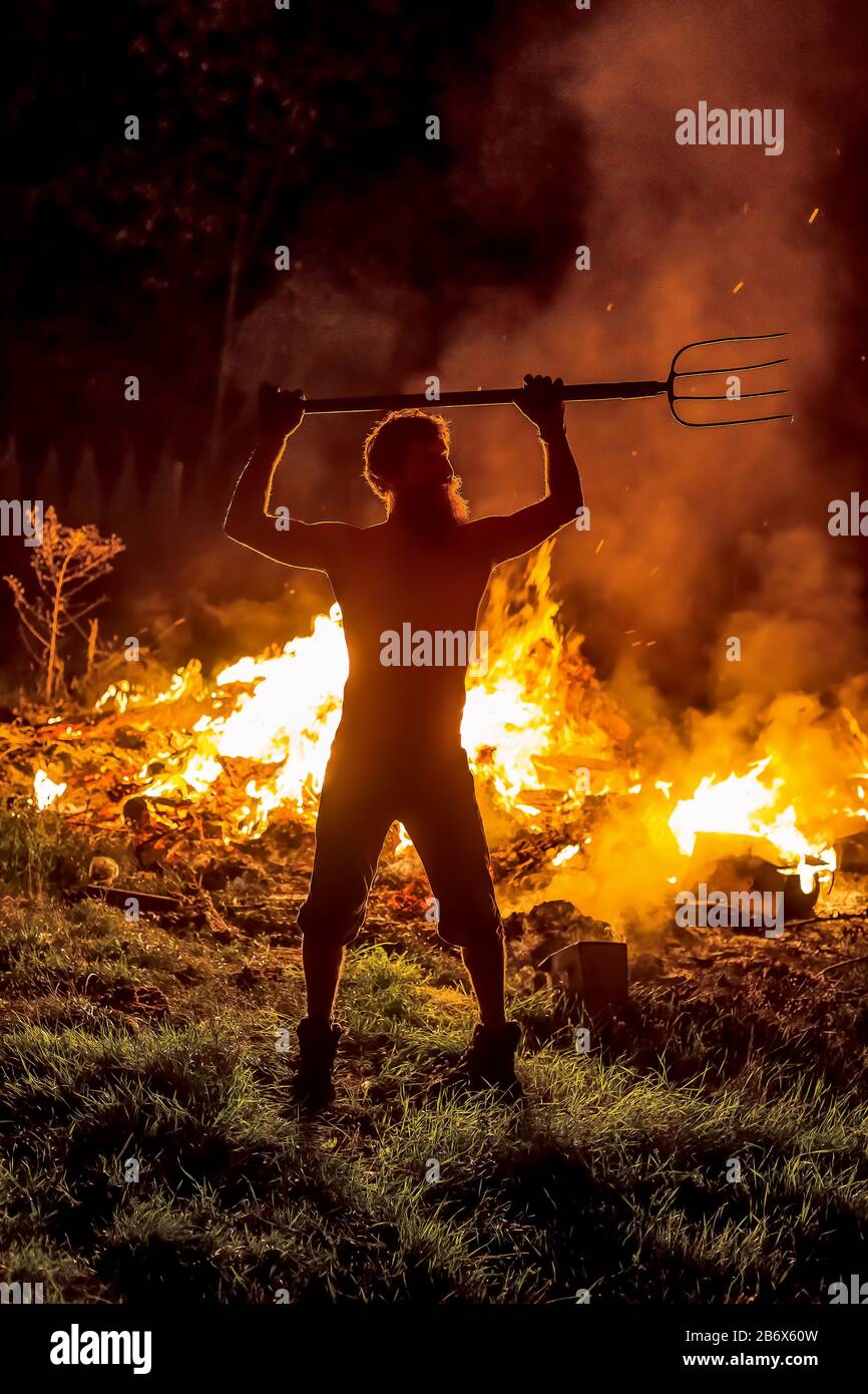 man with pitchfork by the fire, light graphic effect Stock Photo - Alamy