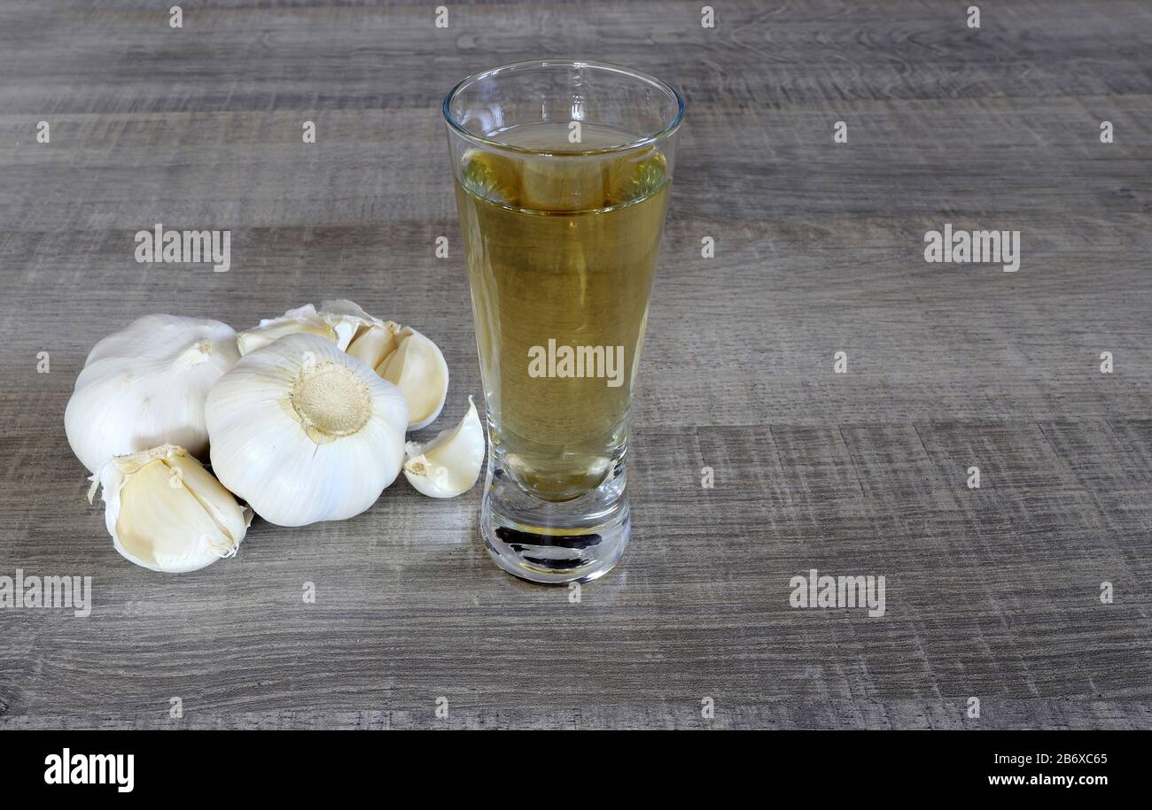 Garlic bulbs and garlic cloves with a glass of alcohol rakia Stock ...