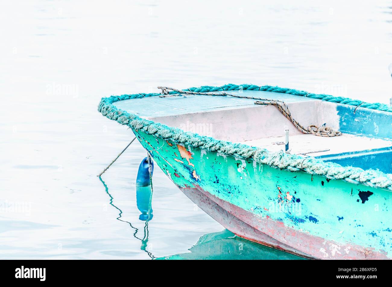 Old shabby boat painted mint green color with flakes of pait falling ...