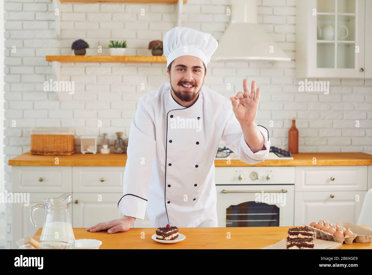 Confectioner man smiles while standing with cake in his hands at the ...