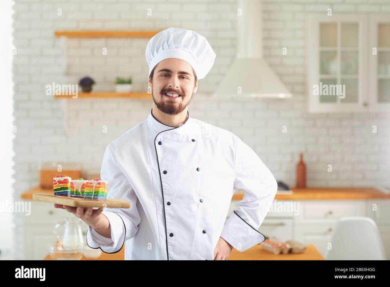 Confectioner man smiles while standing with cake in his hands at the ...