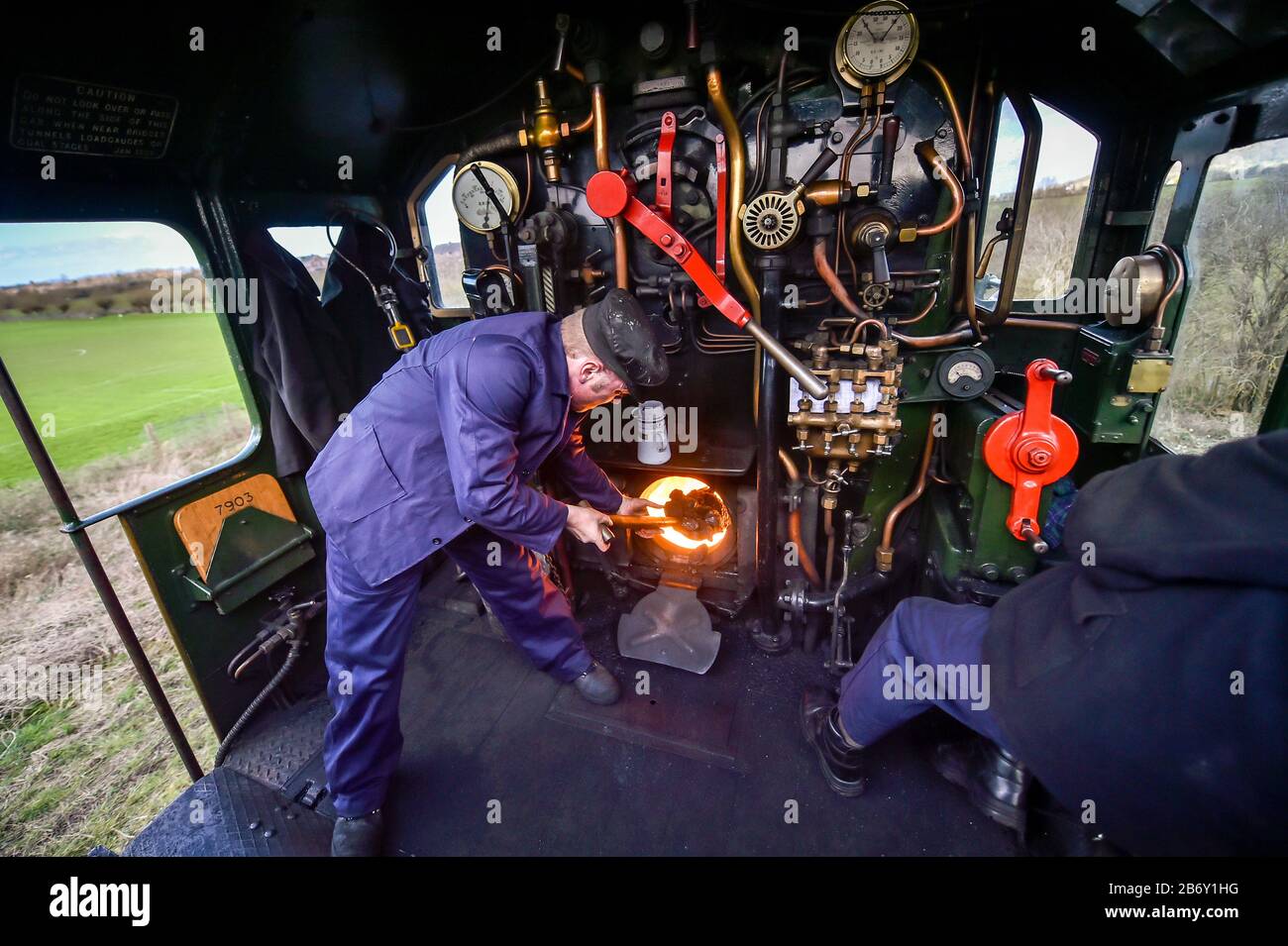Footplate crew shovel coal into the firebox aboard the Great Western ...