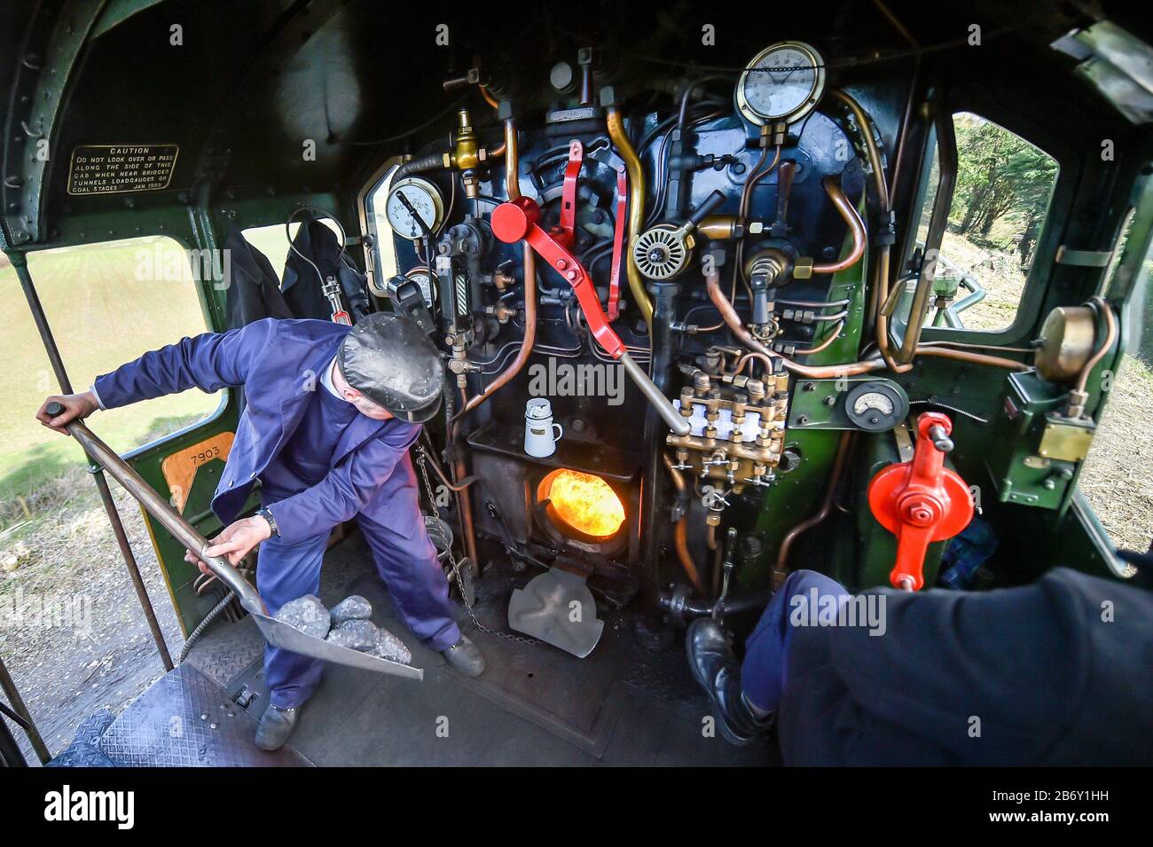 Footplate crew shovel coal into the firebox aboard the Great Western ...