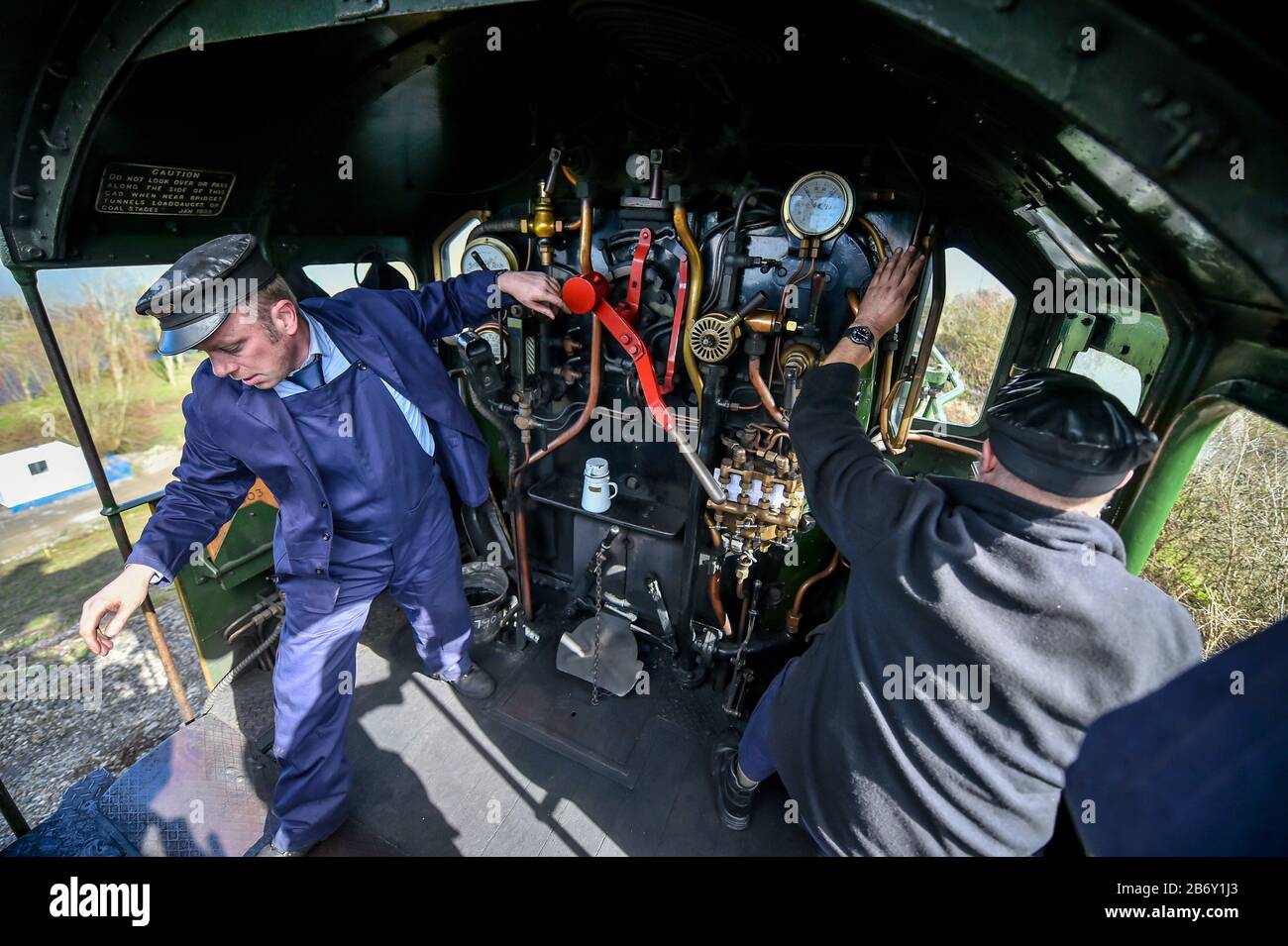 Footplate crew adjust dials and steam regulators aboard the Great ...