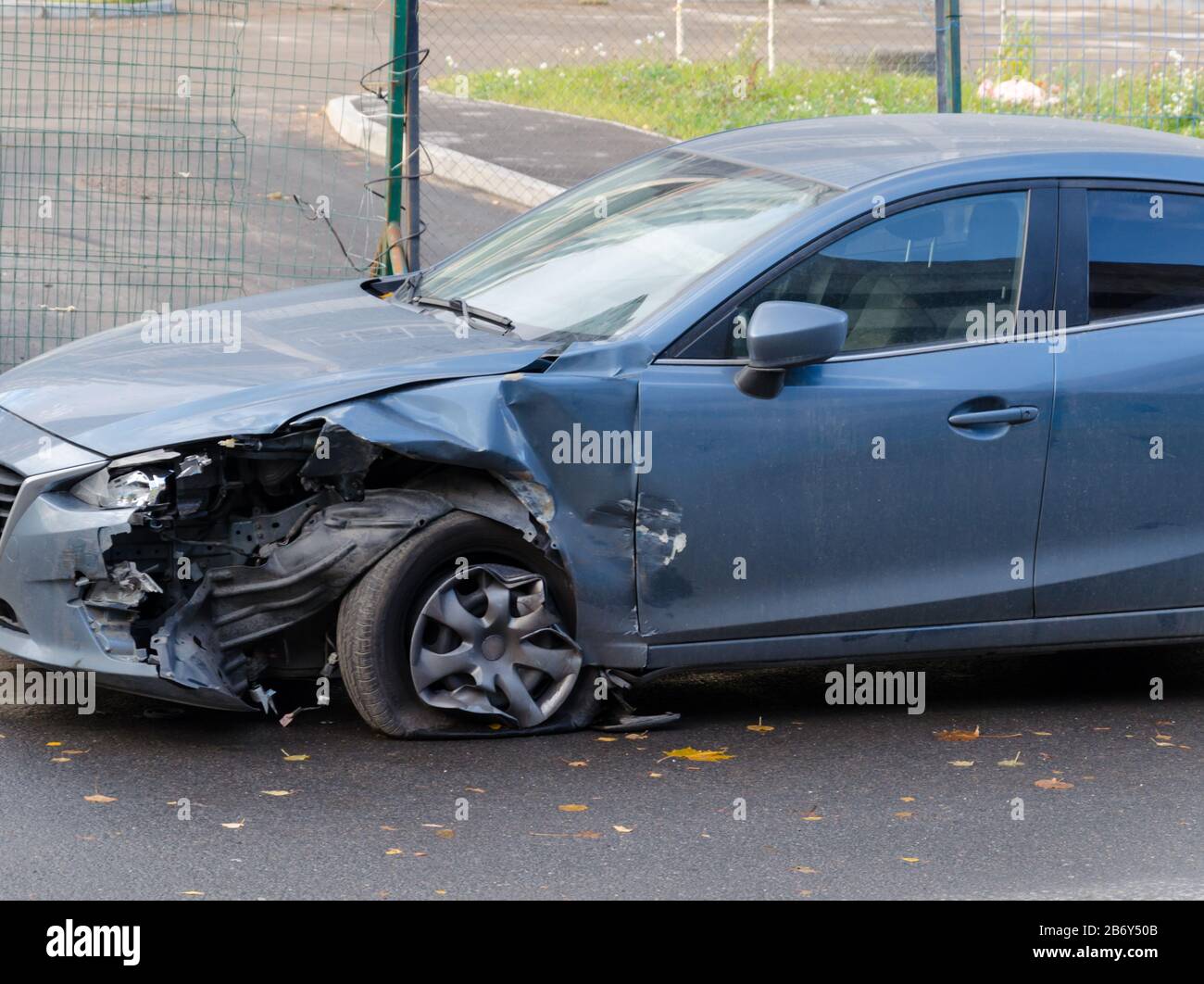 an old blue car after an accident with a broken wing and left door ...