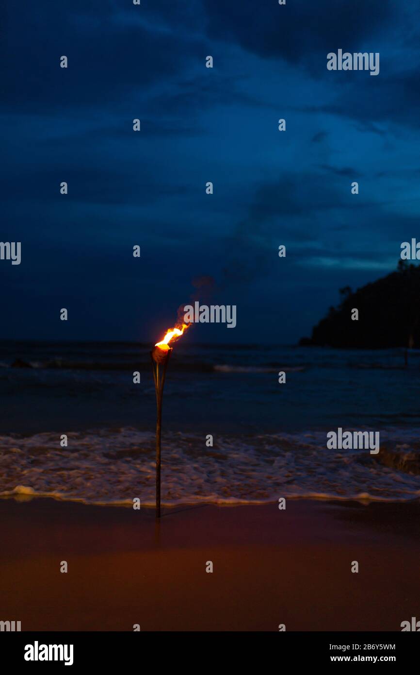 Burning torch on the sandy beach of the ocean Stock Photo - Alamy