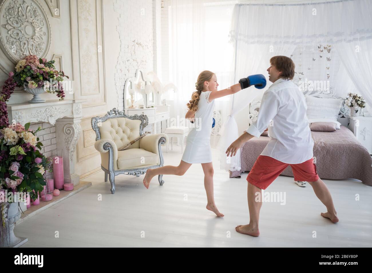 Little teenage girl fights with her dad using boxing gloves while ...