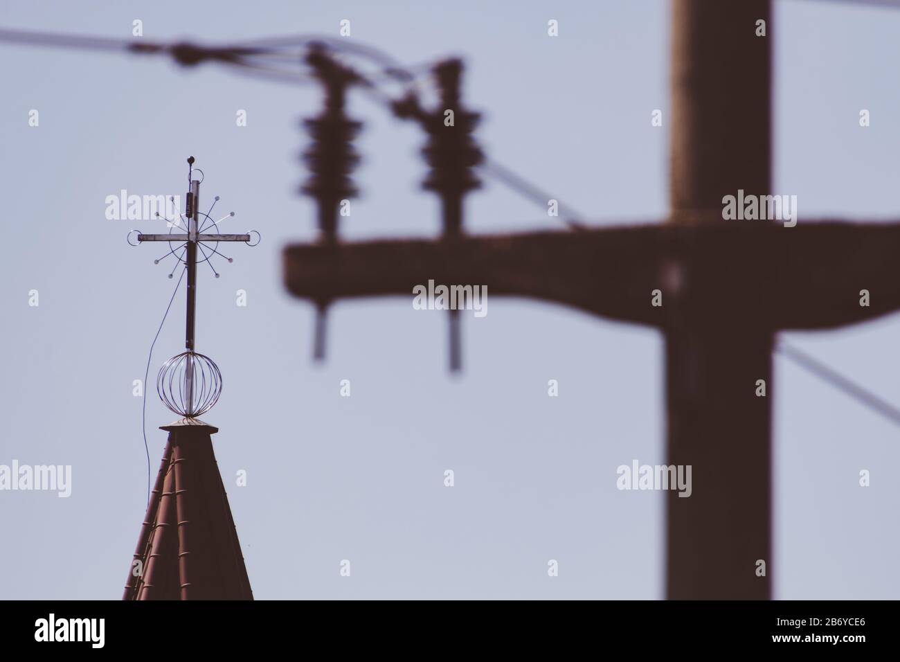 Church roof cross with faded power line on power pylon in the ...