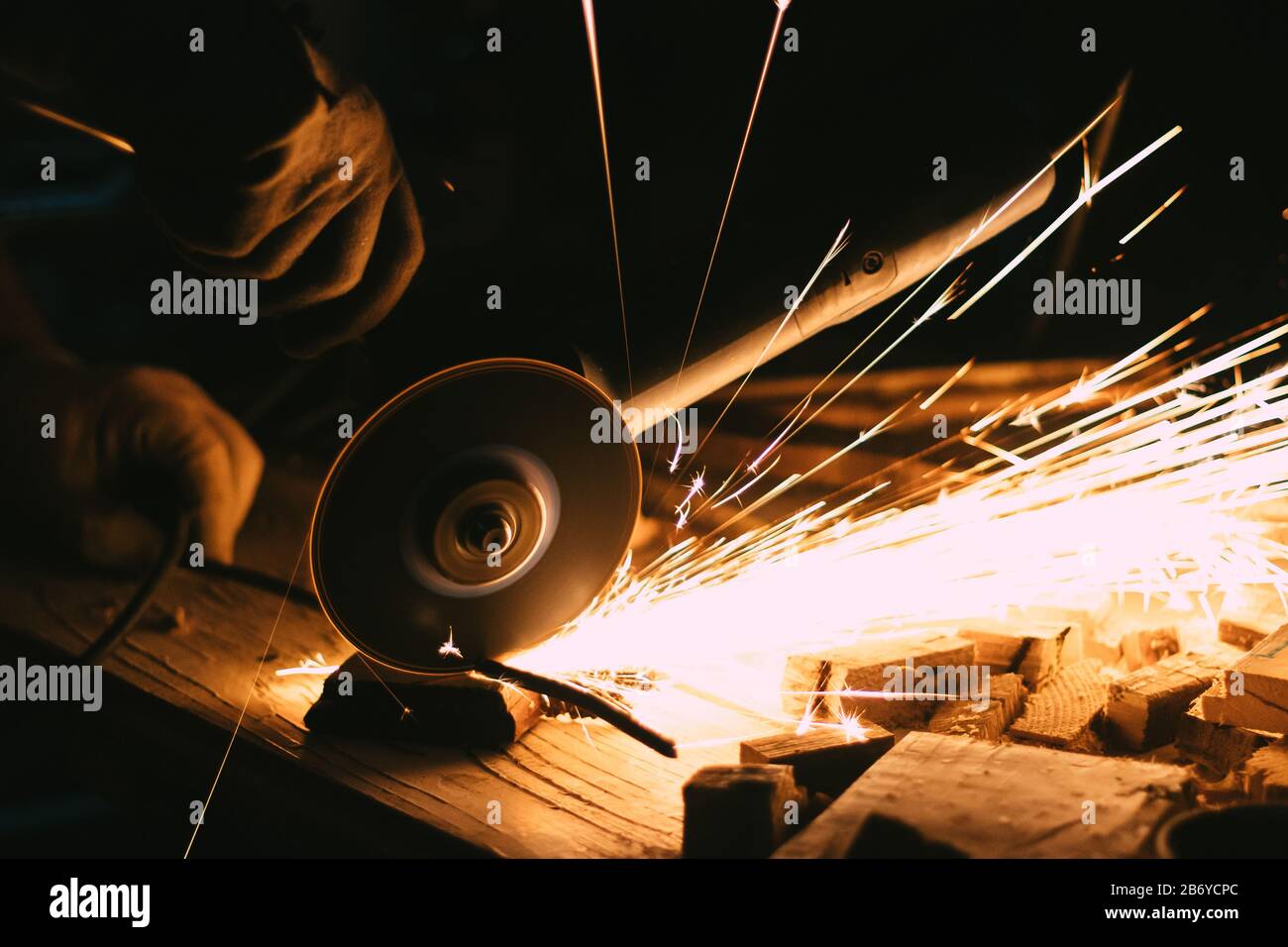 Man cutting a piece of metal with an angle grinder with sparks jumping ...