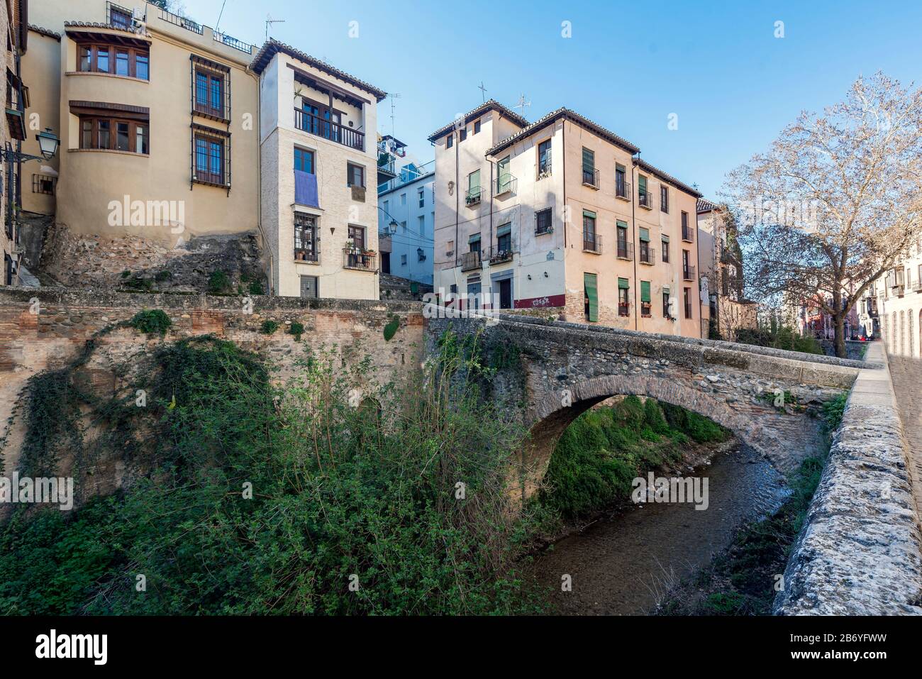 The Darro River on its way through Granada with a bridge and people ...