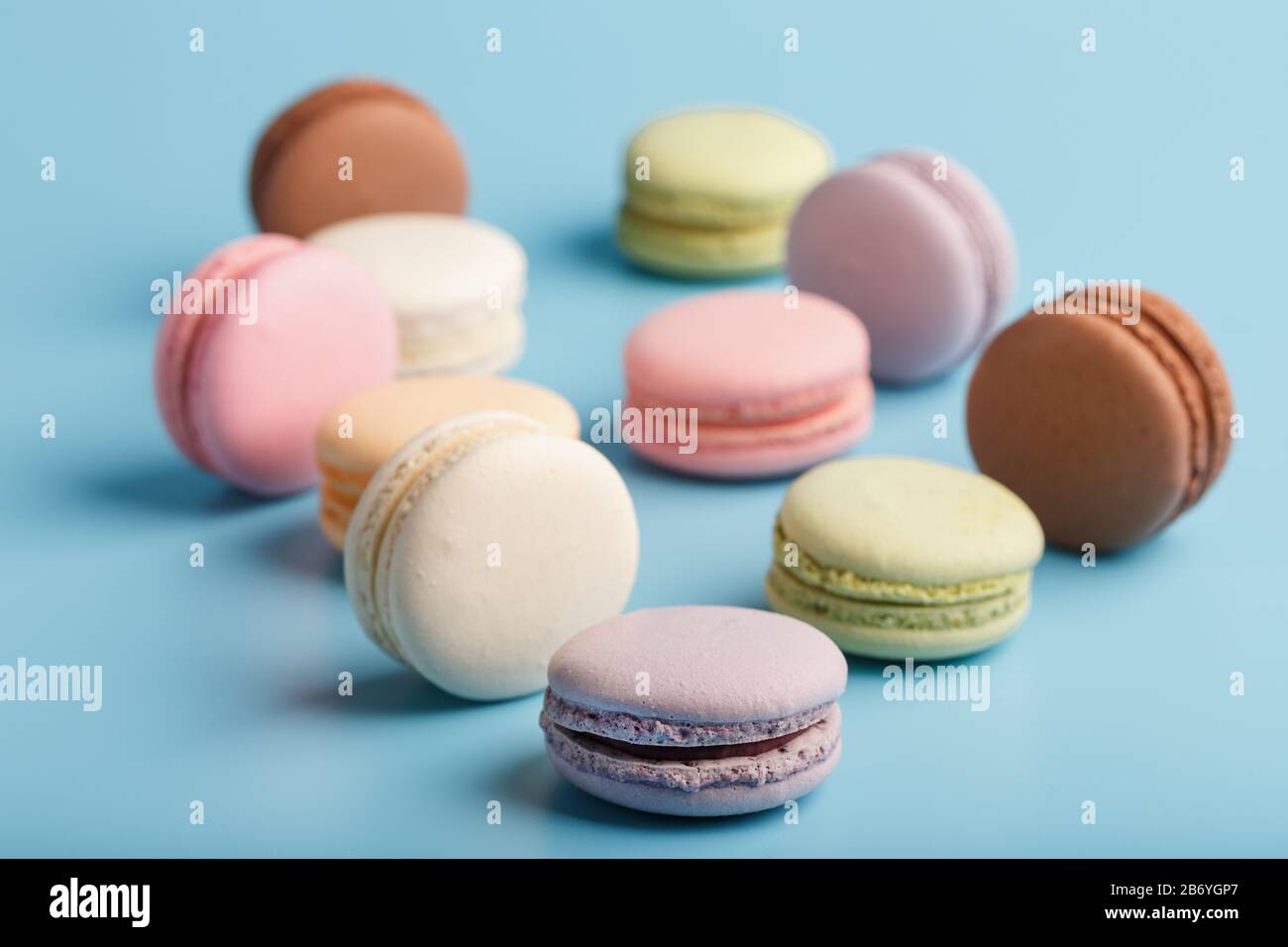 Macaroni cookies of different colors are scattered on a blue background ...