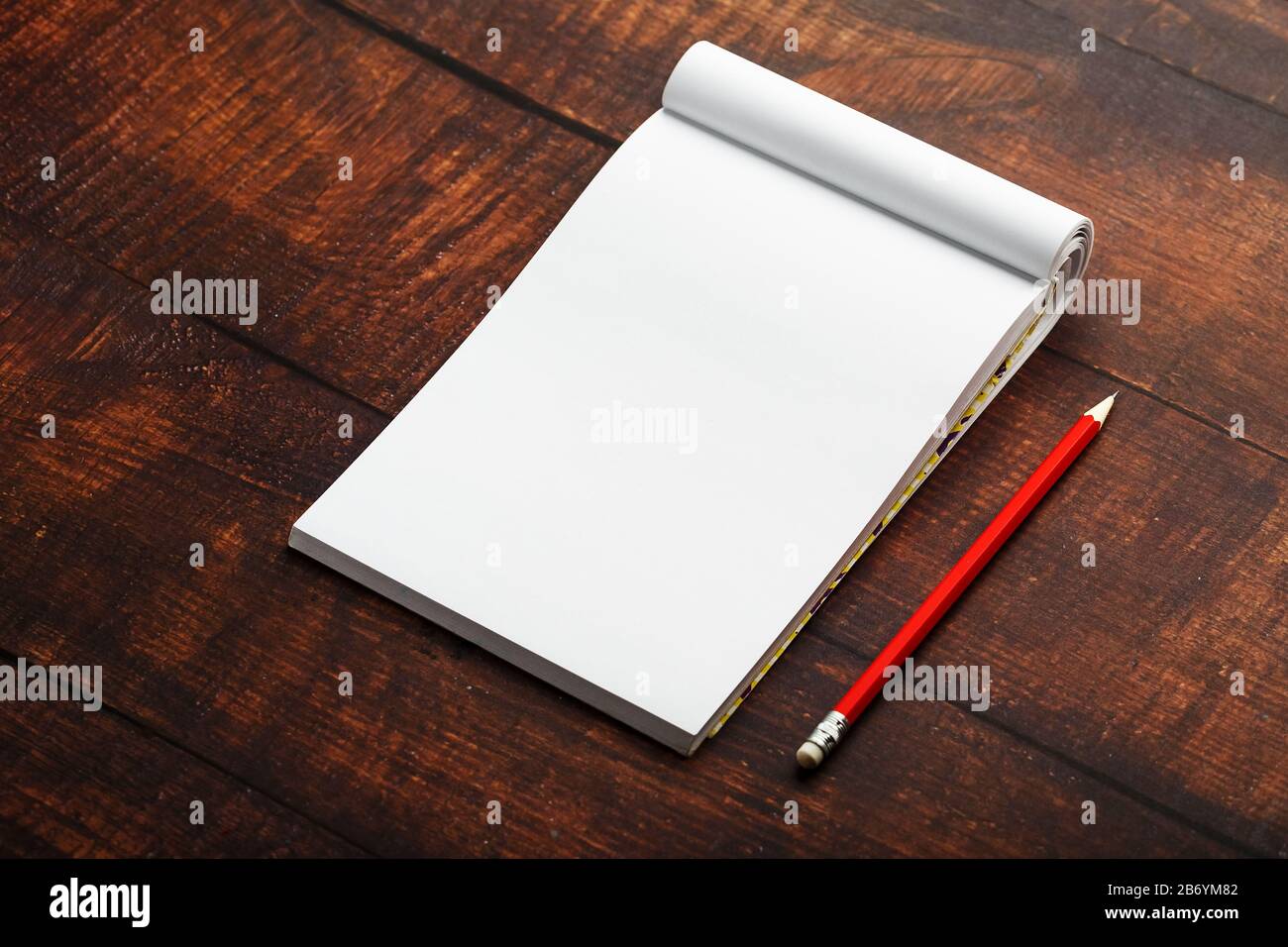Notepad with red pencil on a brown wooden table background, for ...