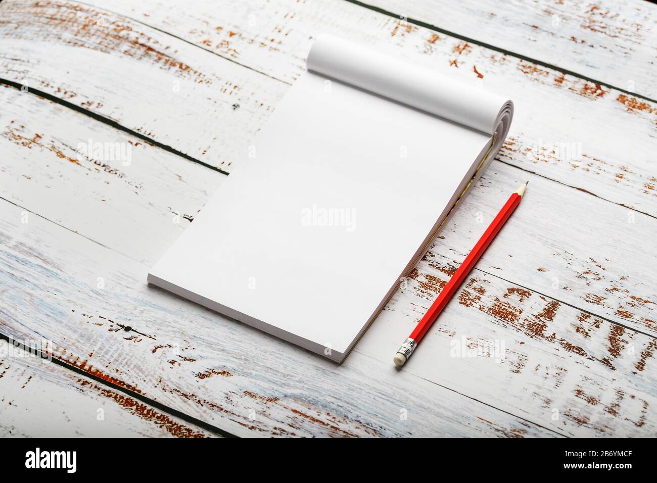 Notepad with a red pencil on a white wooden table against the ...