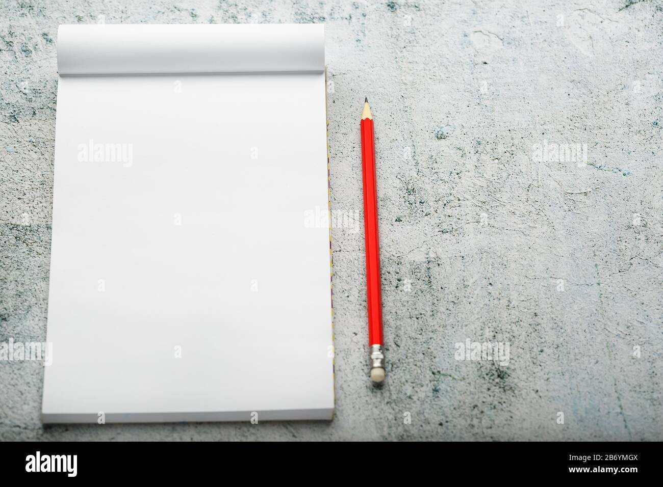 Notepad with red pencil on white plastered wall background, for ...