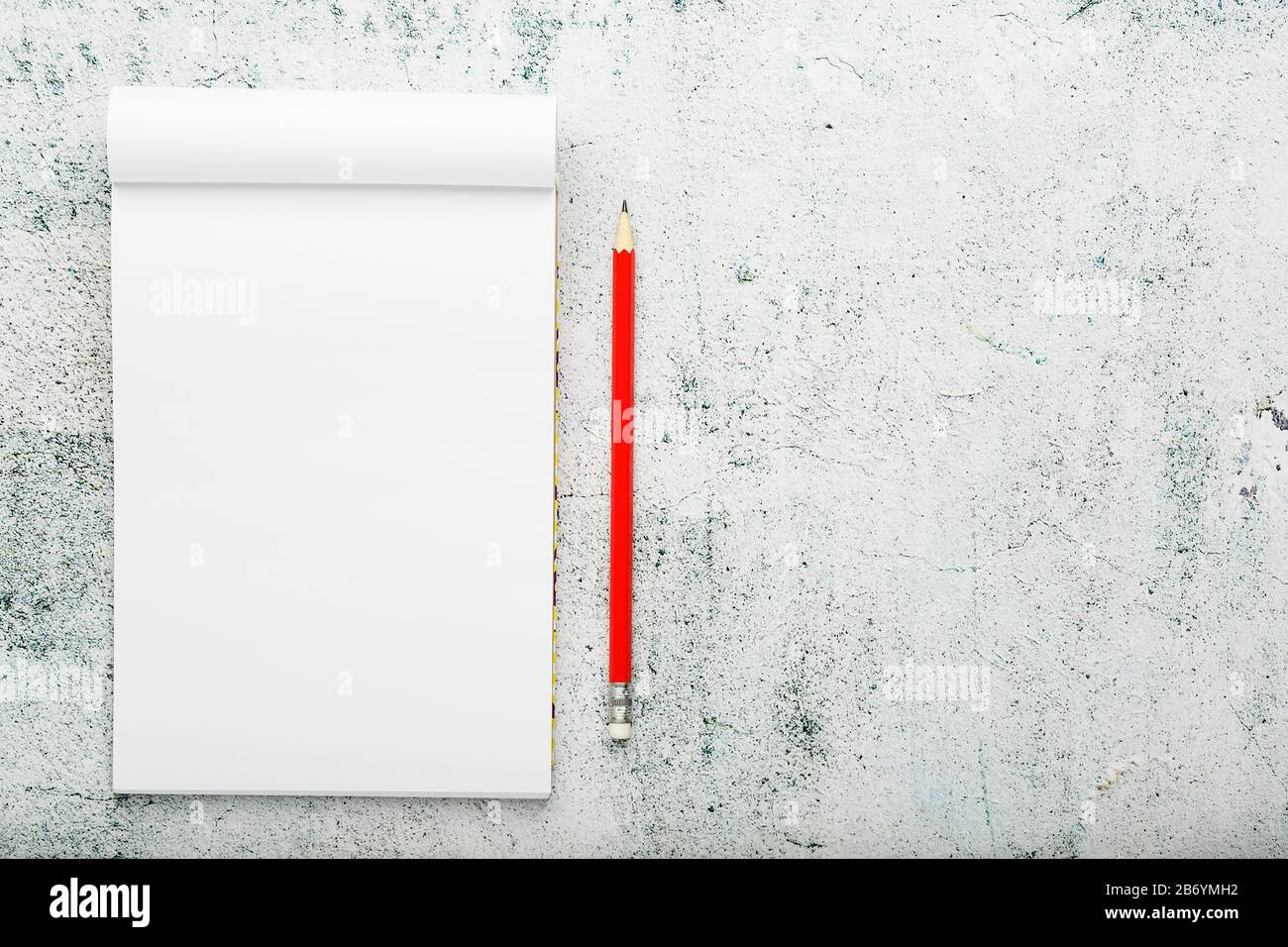 Notepad with red pencil on white plastered wall background, for ...