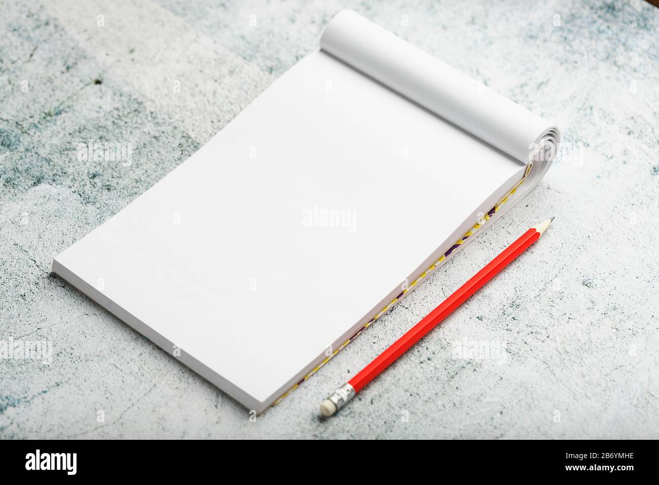 Notepad with red pencil on white plastered wall background, for ...