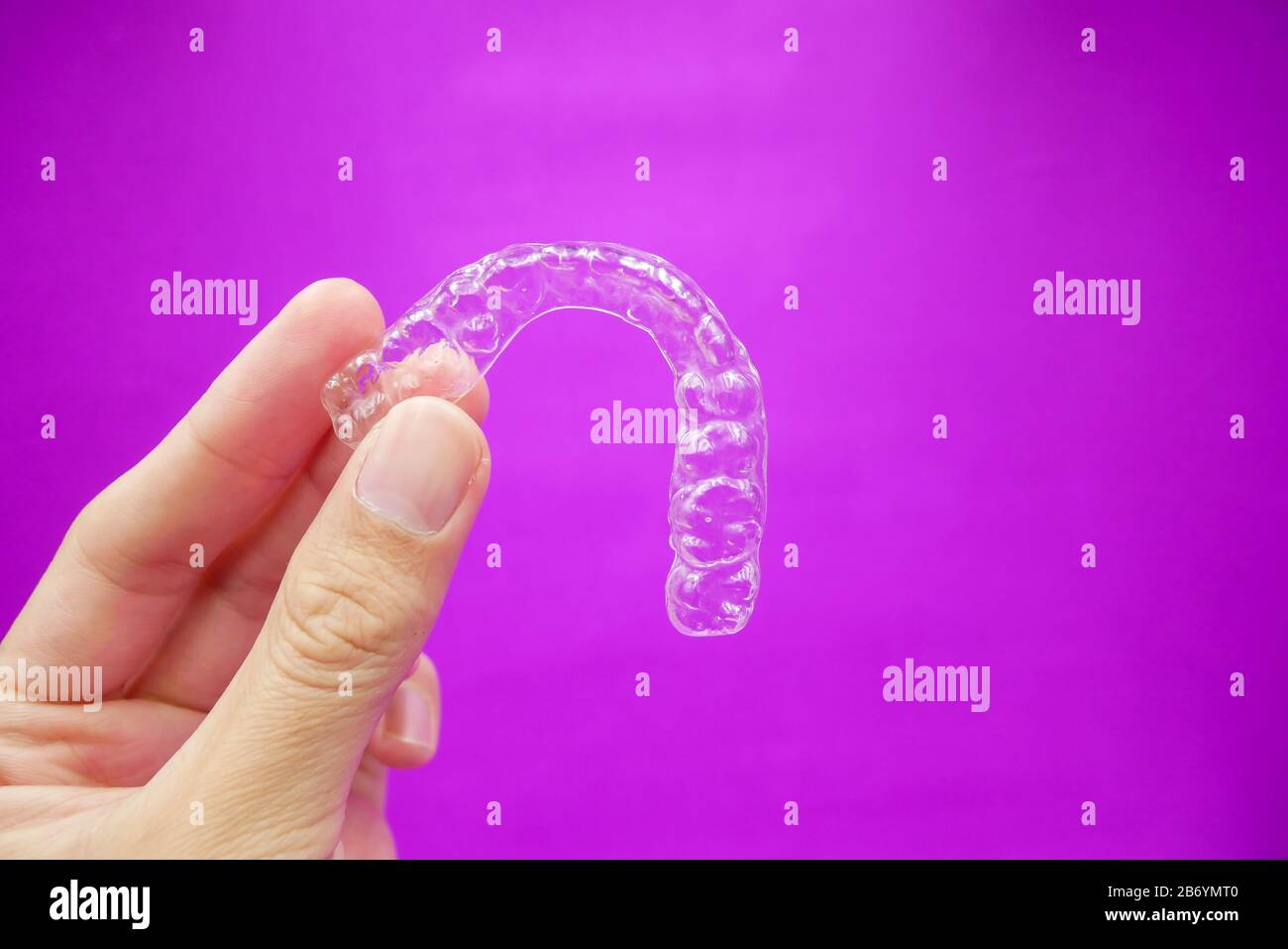 hand holding clear plastic retainer teeth that isolated on purple ...