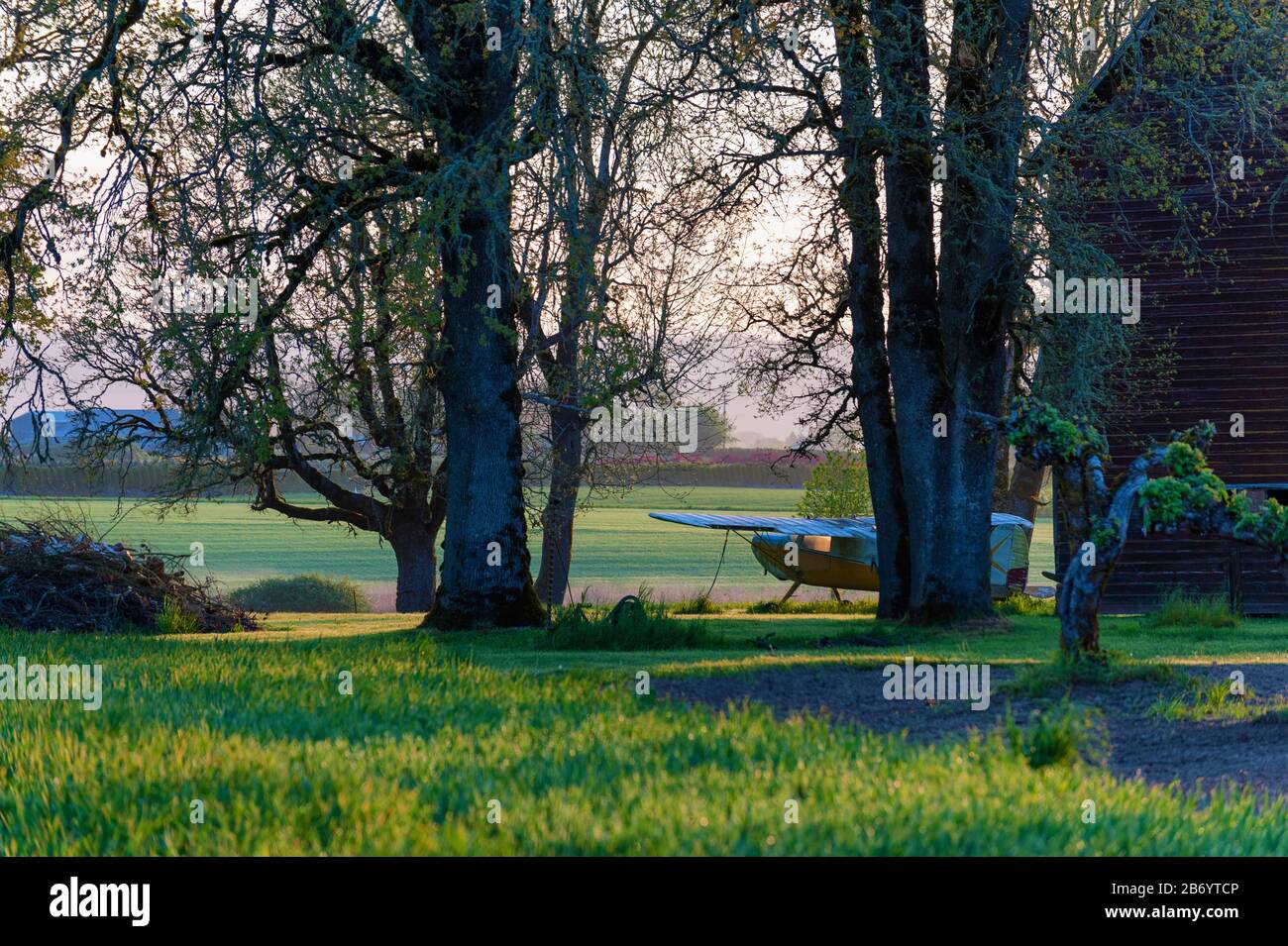 A plane sit next to a barn as early morning light brightens the ...