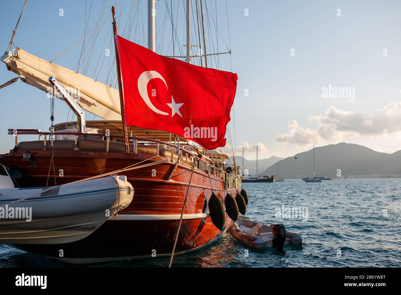 Beautiful wooden yacht with the big flag of Turkey on the pier, against ...