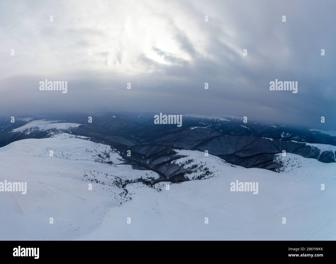 Stunning view of the cliffs covered with snow and trees on a cloudy ...