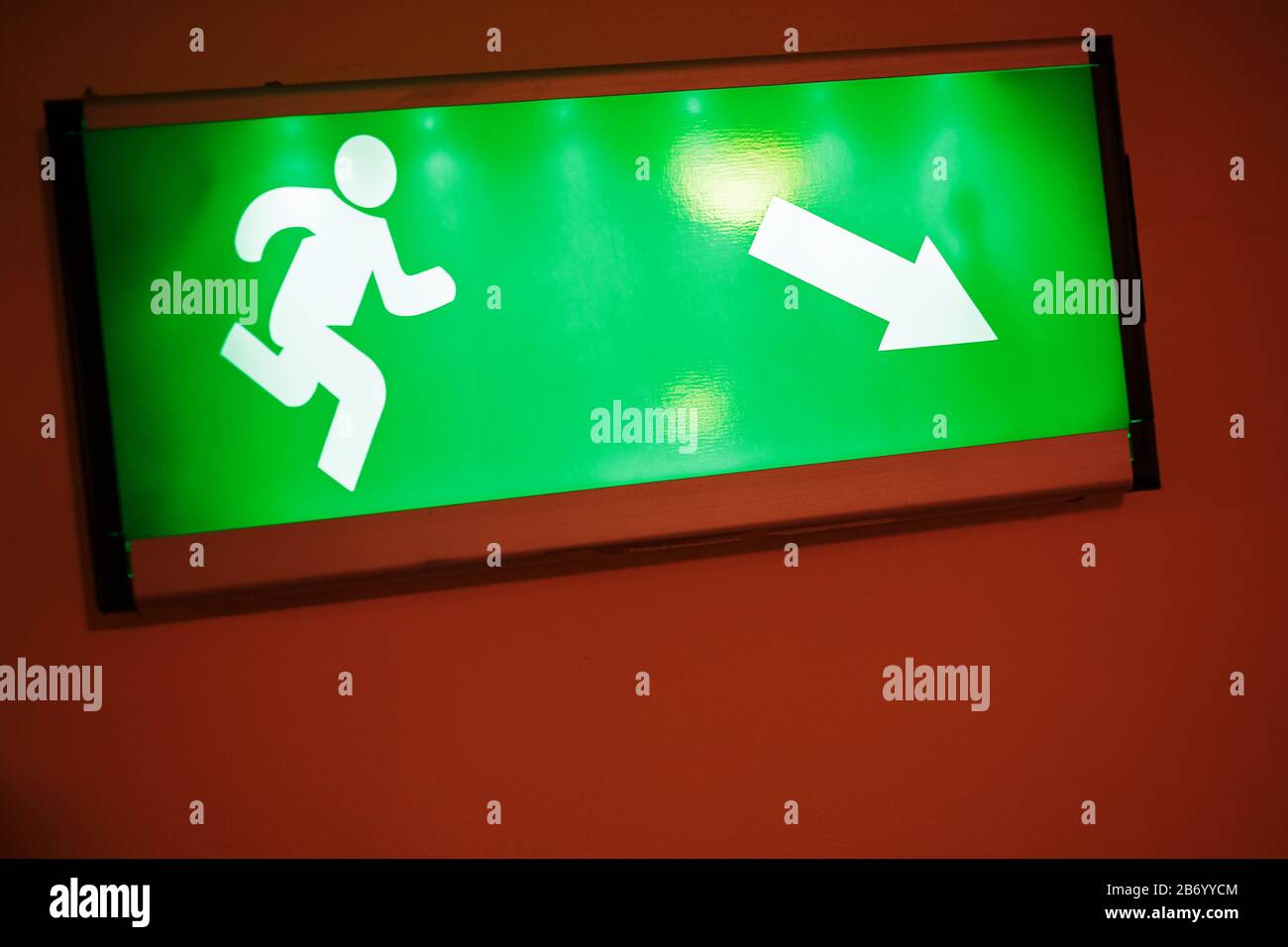 Green escape route sign on a flight of stairs. The man with the arrow ...