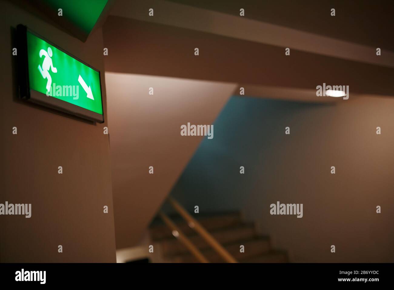 Green escape route sign on a flight of stairs. The man with the arrow ...