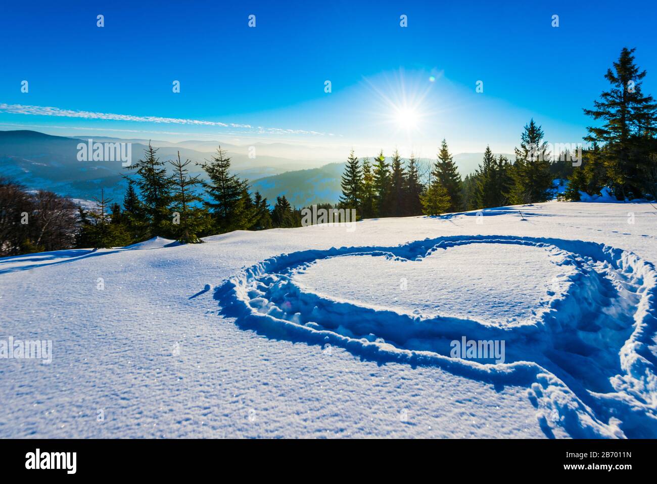 Heart trampled on the snow with feet in a snowdrift on a hillside with ...