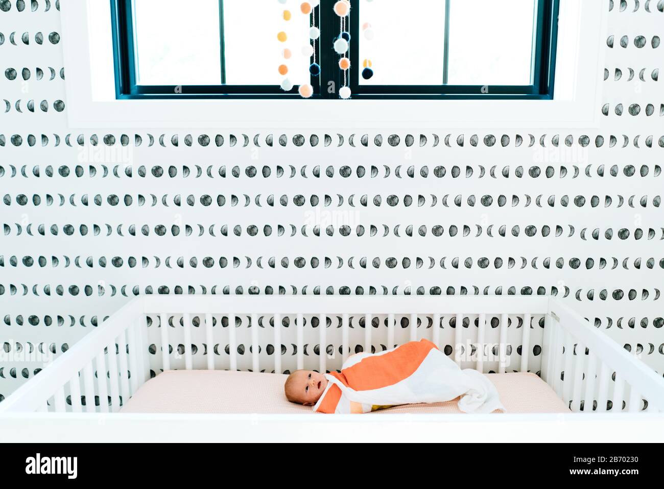 Wide angle view of a newborn baby girl lying down in a modern nursery ...