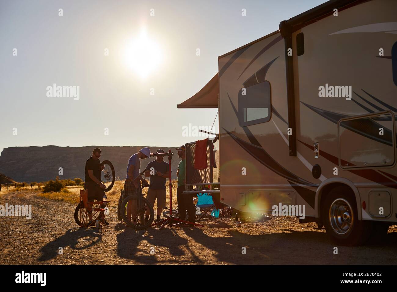 A group of guys working on mountain bikes at the rear of an RV Stock ...