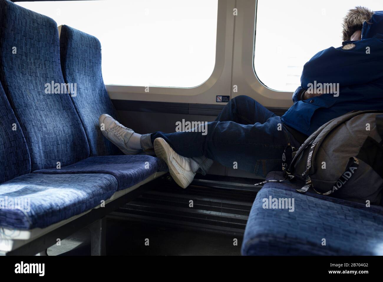 The white trainer shoes of a sleeping rail passenger are on a train ...