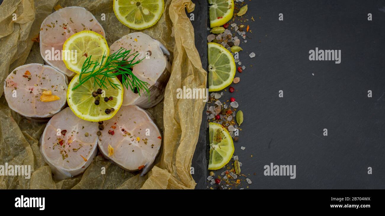 fresh fish fillets of conger eel ,lemon herbs , pepper, salt on black ...