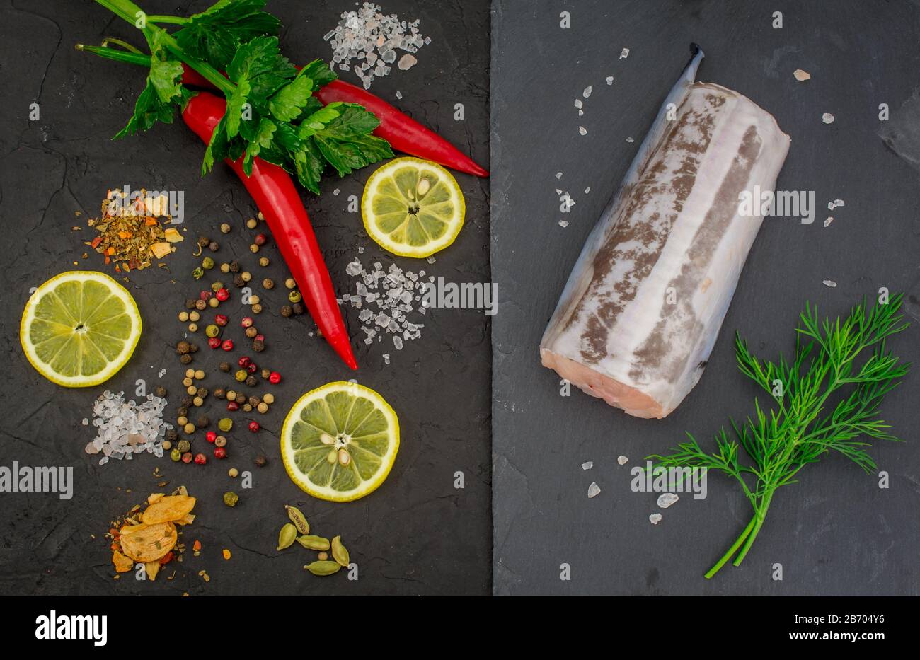 fresh fish fillets of conger eel ,lemon herbs , pepper, salt on black ...