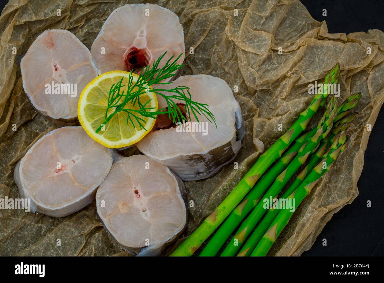 fresh fish fillets of conger eel ,lemon herbs , pepper, salt on black ...