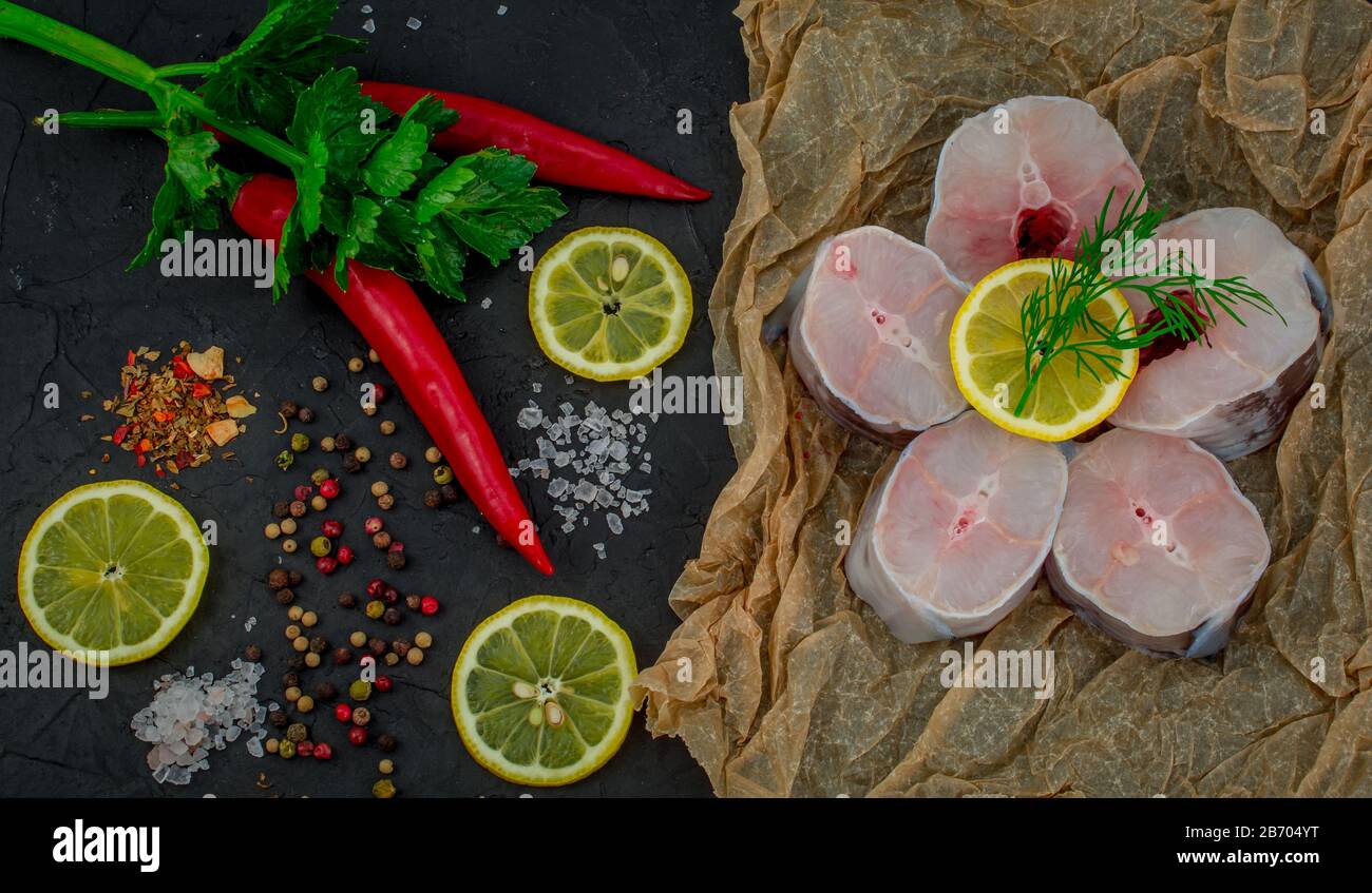 fresh fish fillets of conger eel ,lemon herbs , pepper, salt on black ...