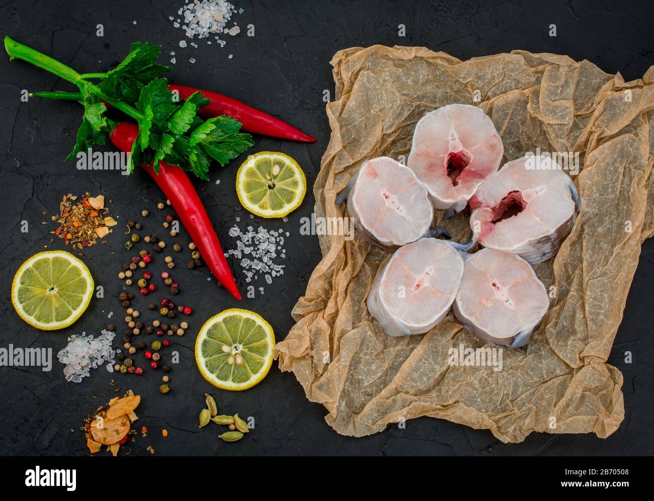 fresh fish fillets of conger eel ,lemon herbs , pepper, salt on black ...