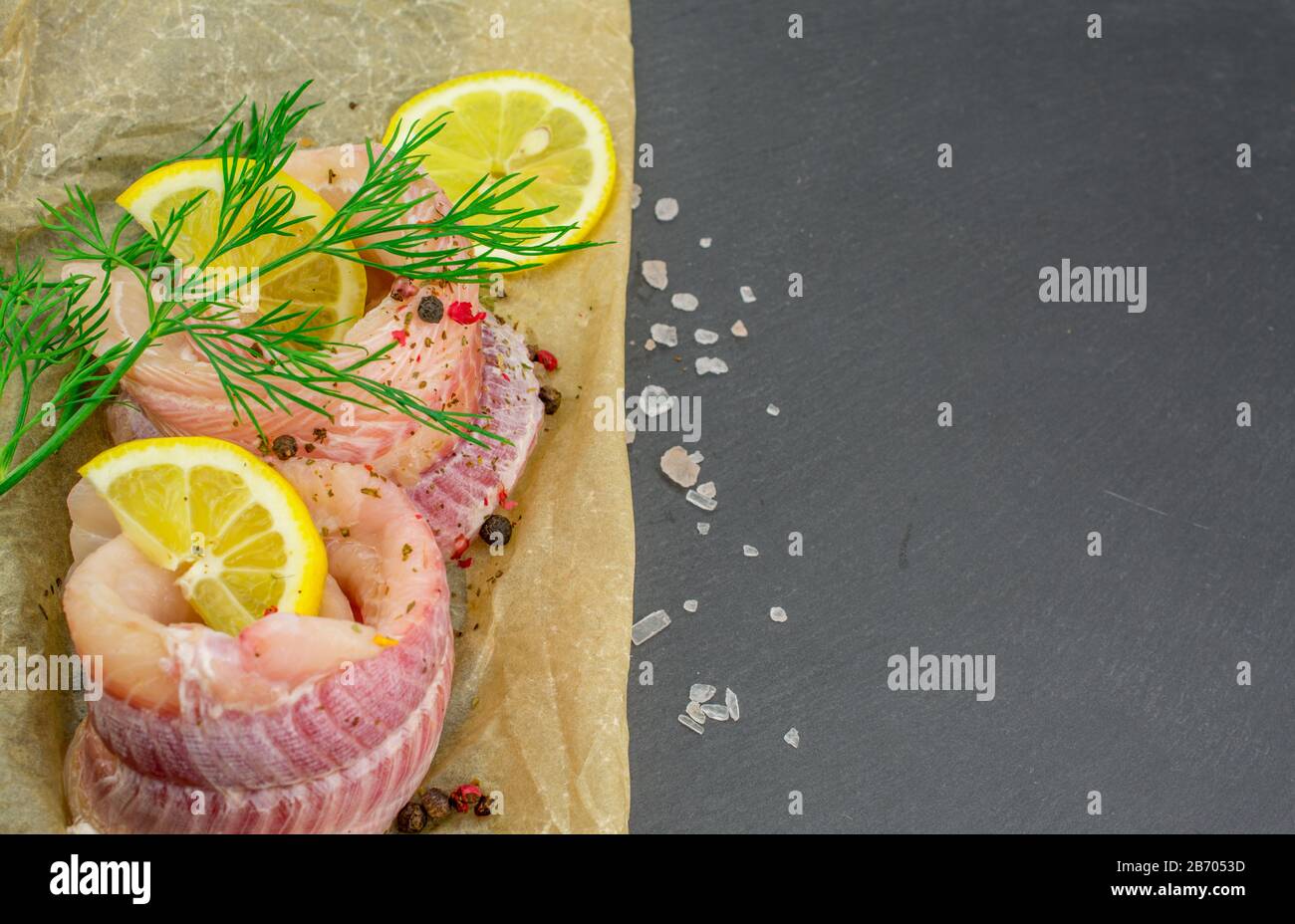 fish fillets of dogfish with lemon herbs on black background Stock ...