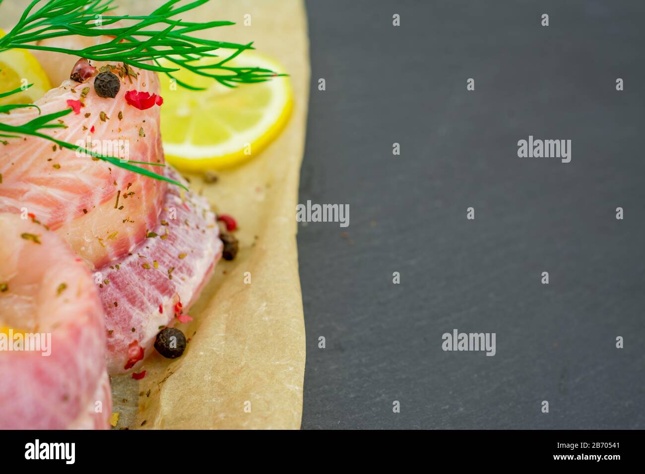 fish fillets of dogfish with lemon herbs on black background Stock ...
