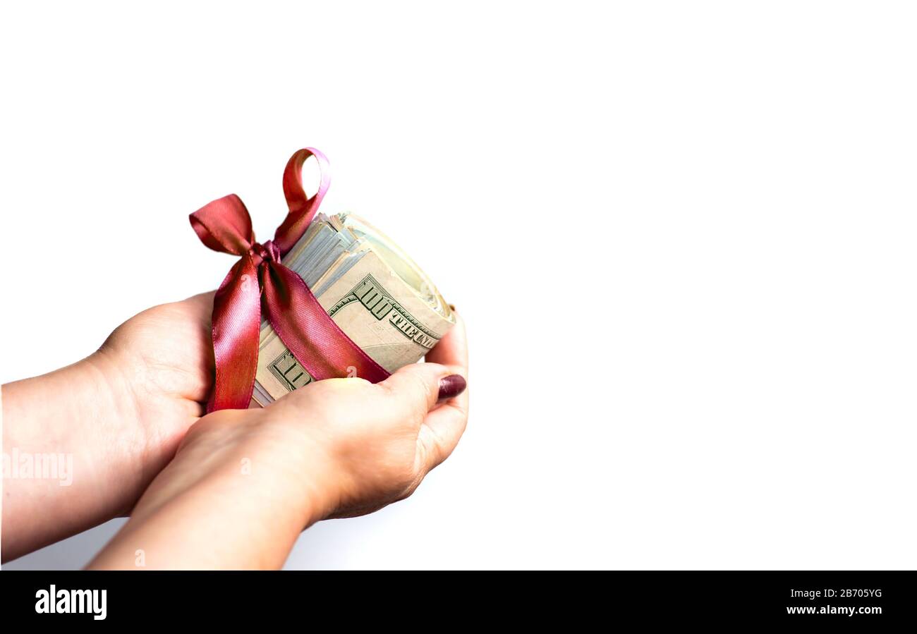 US dollars gift. Female hands tying a bow with purple ribbon on a pile ...