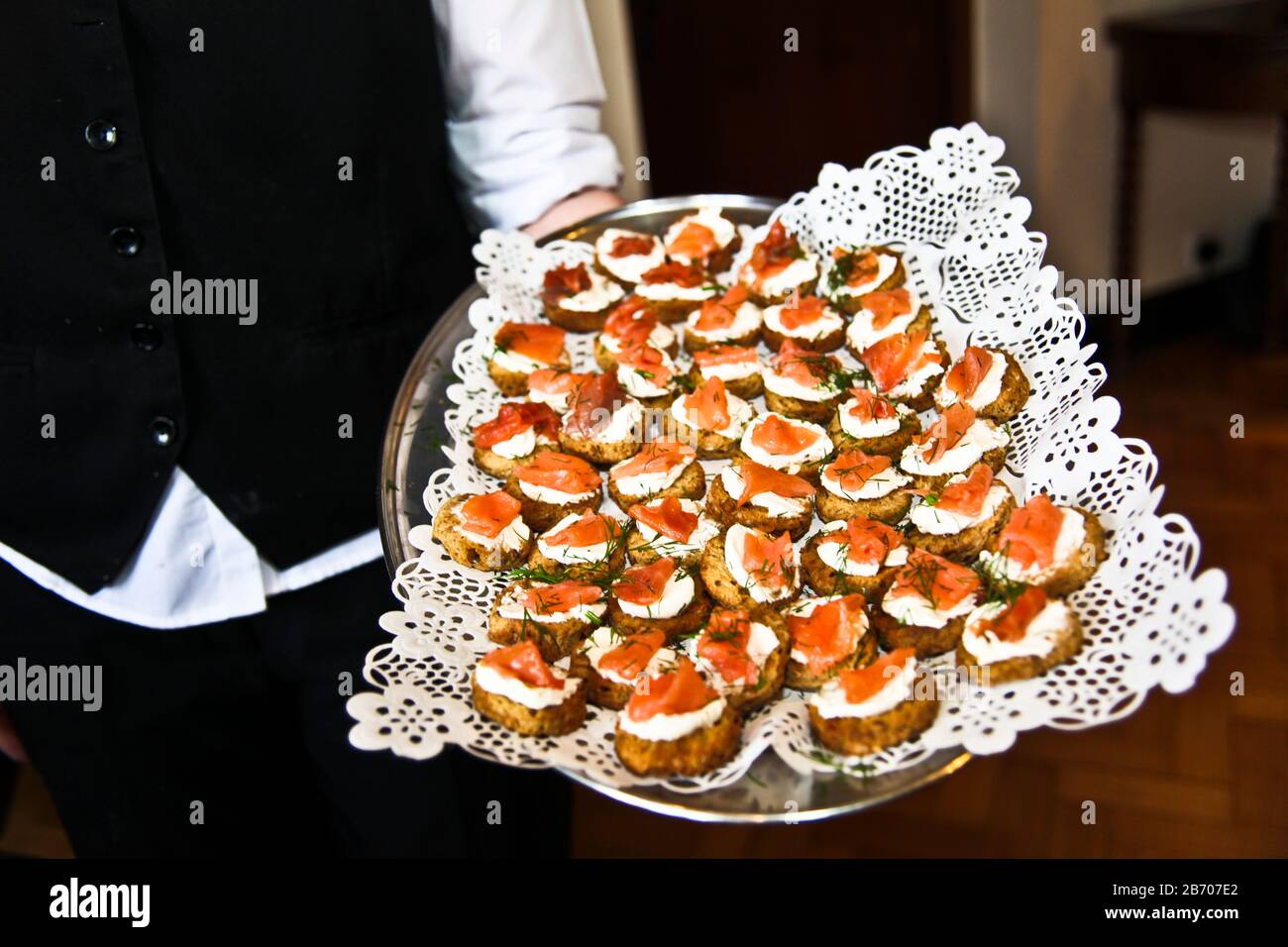 a tray with salmon canapés shown by a waiter Stock Photo - Alamy