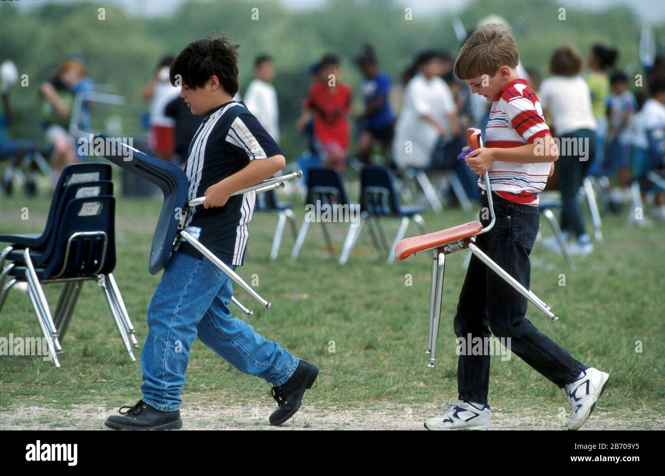 Austin, Texas USA: Elementary school students carry plastic chairs onto ...