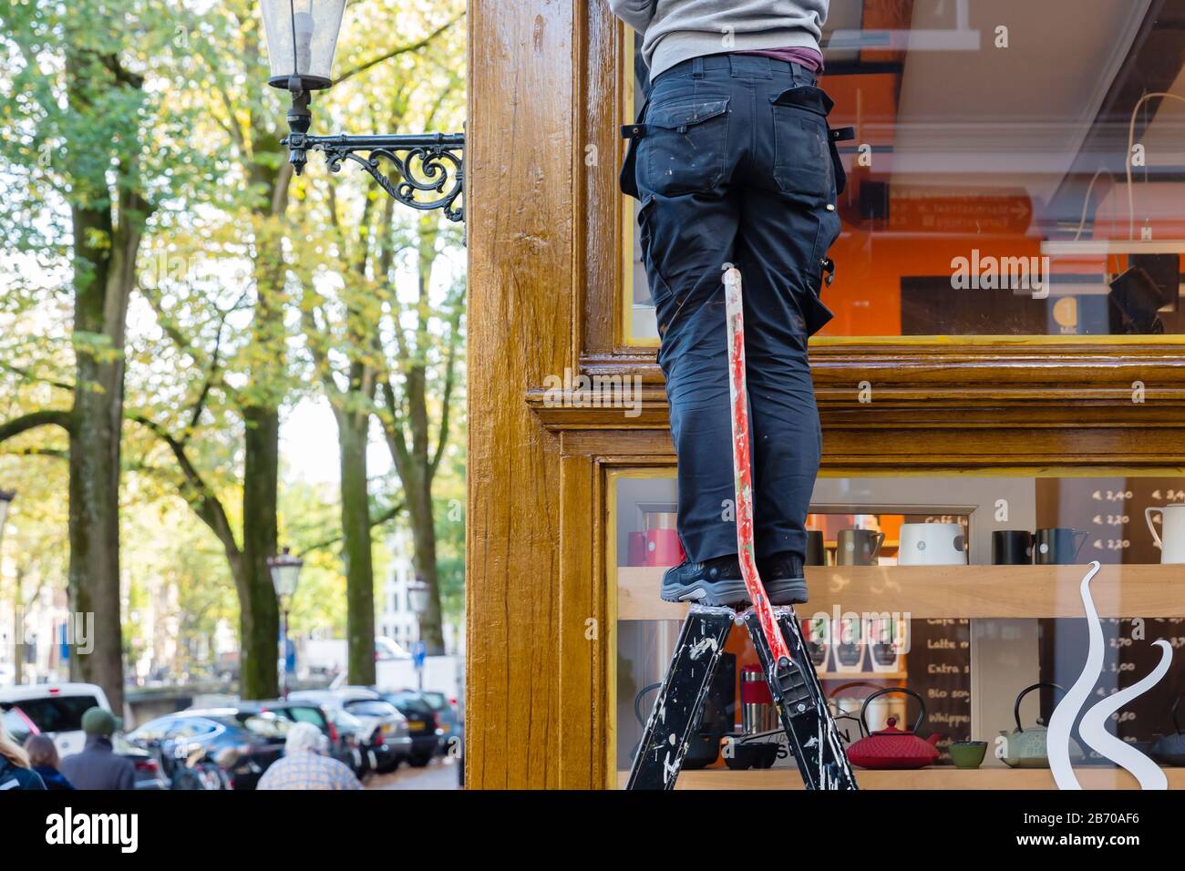 worker standing on a ladder working something at the building of a shop ...