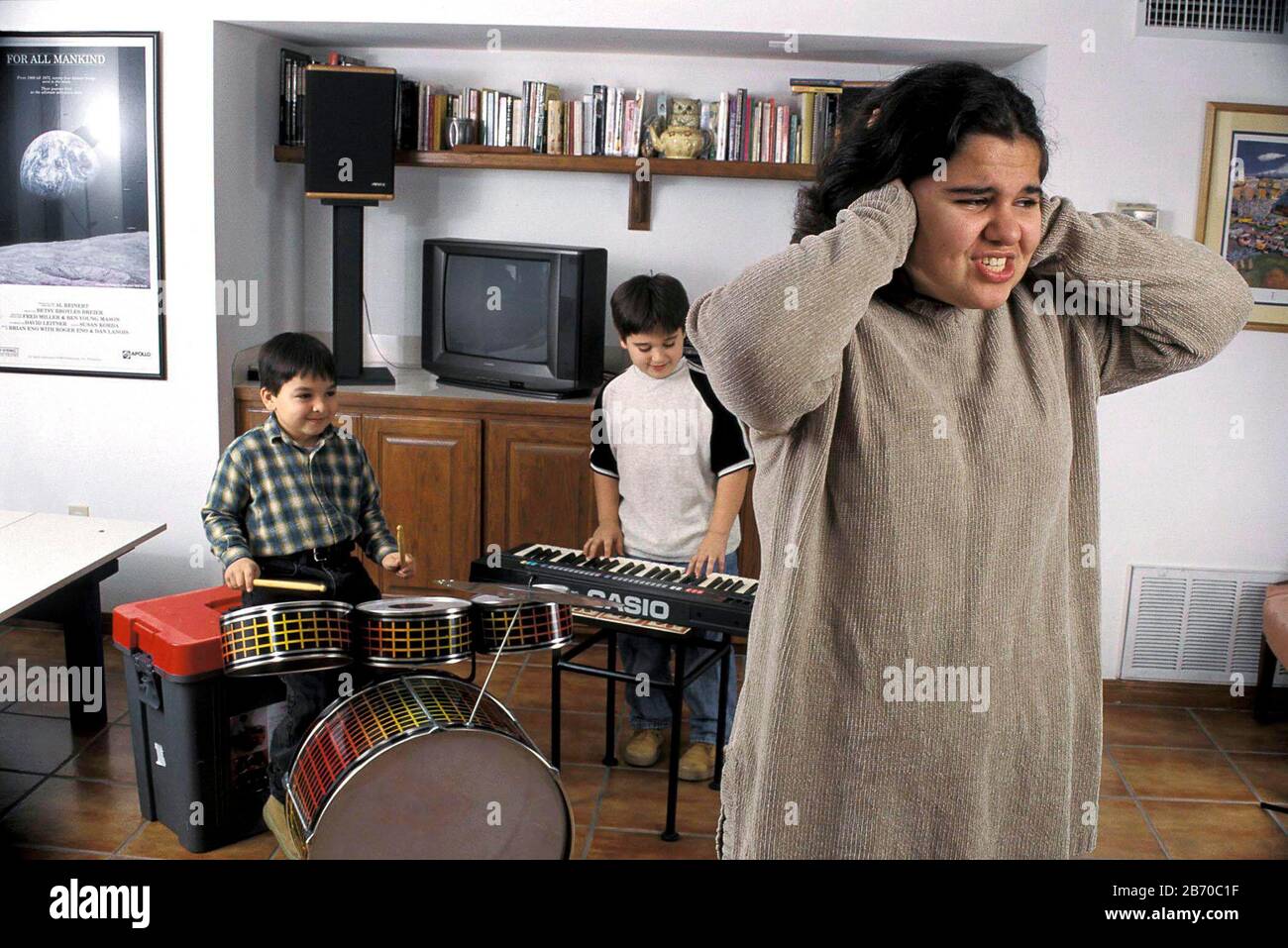 Young boys playing loud music inside home, while teenage sister covers ...