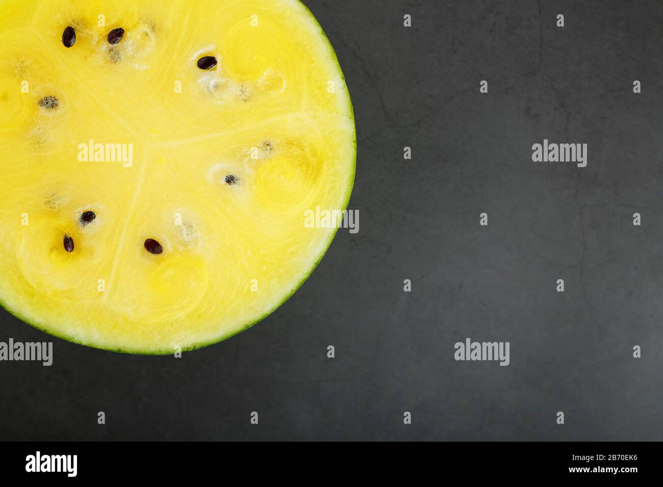 Half of tasty and ripe yellow watermelon on a black background, texture ...