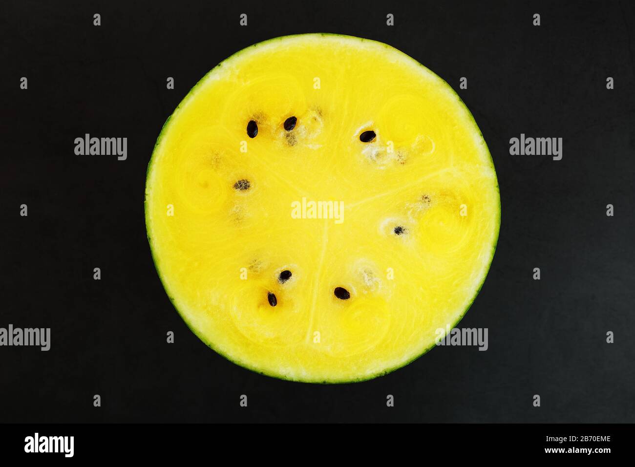 Half of tasty and ripe yellow watermelon on a black background, texture ...