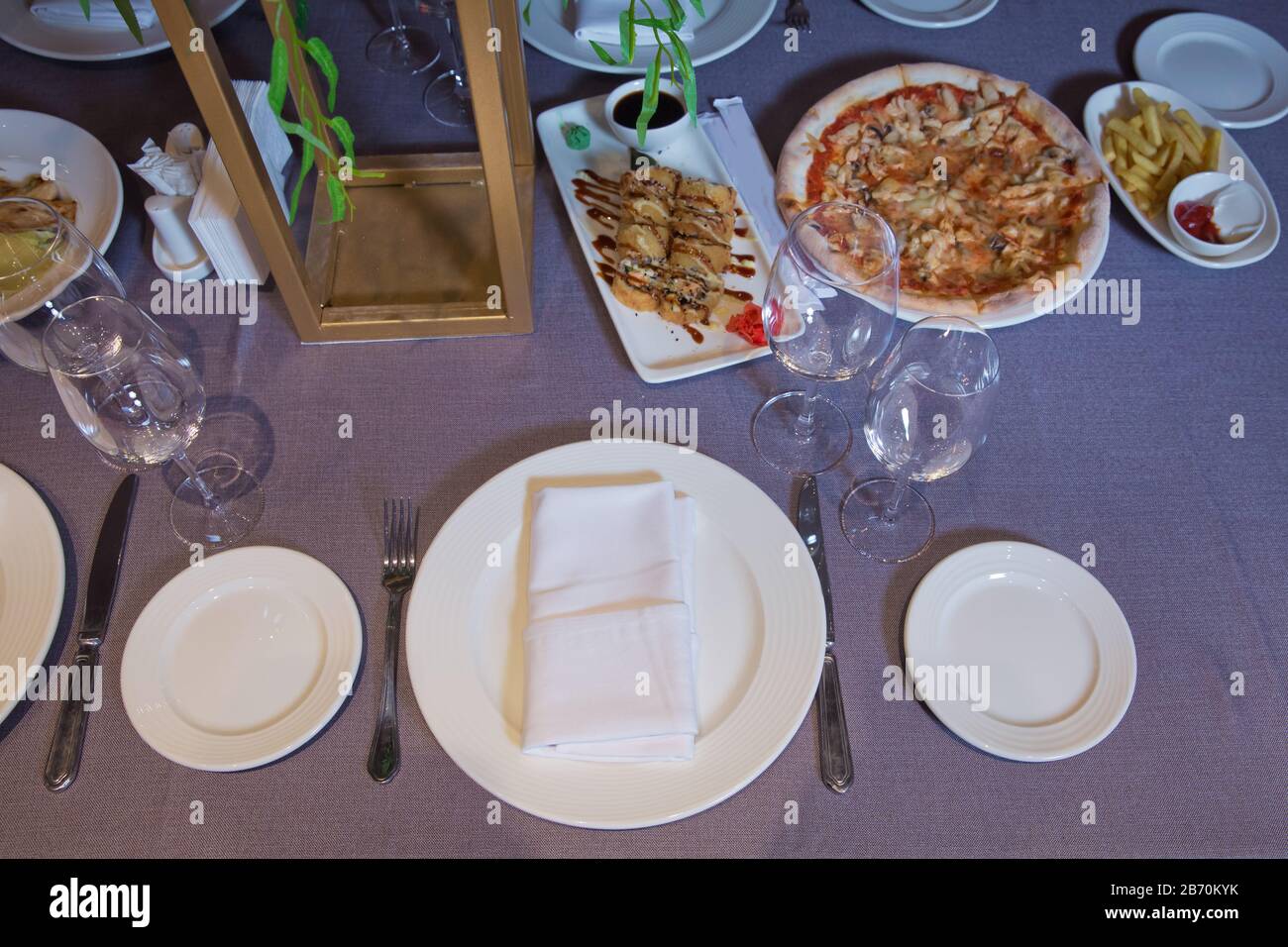 Tables set for meal . fork, knife , table towel . Pizza, potato fries ...