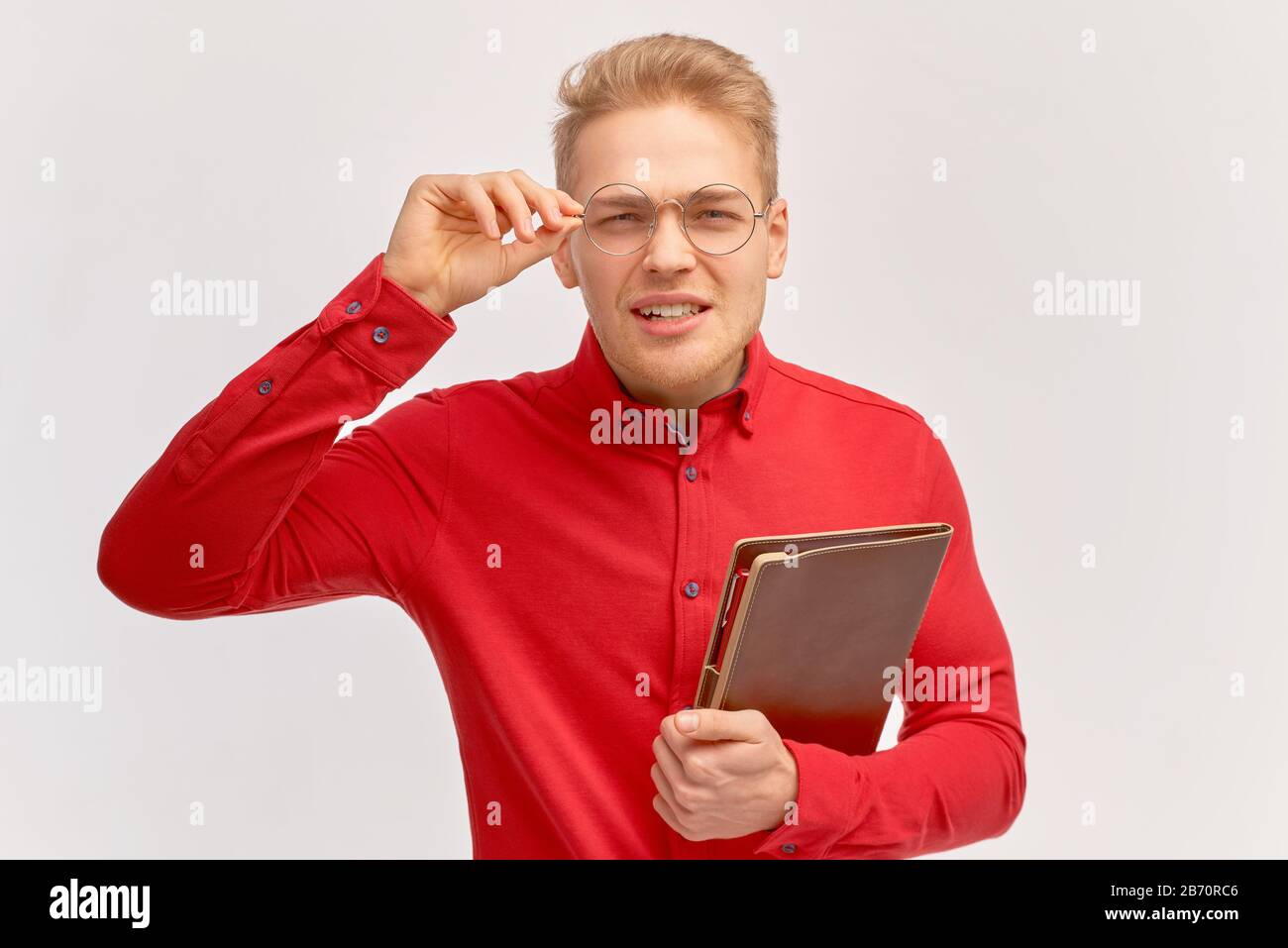 Shocked man keeps hand on rim of spectacles Stock Photo - Alamy
