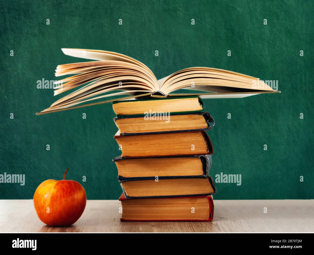 Back to school, pile of books and red apple with empty school board ...